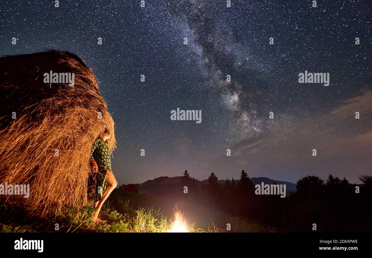 Young woman near a haystack and campfire against the backdrop of a ...