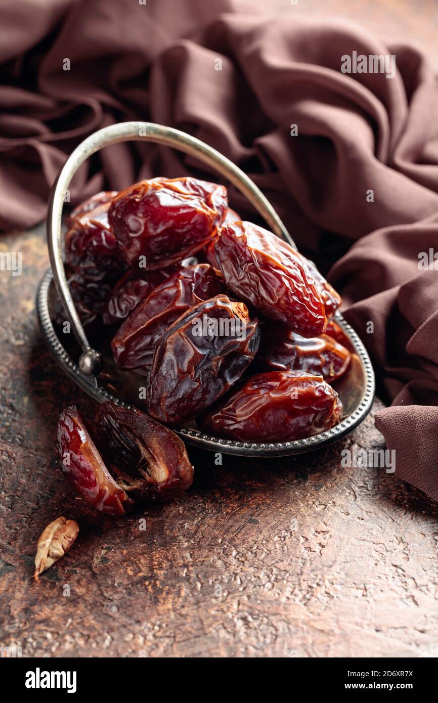 Dried sweet dates in a metal dish on an old brown table Stock Photo - Alamy