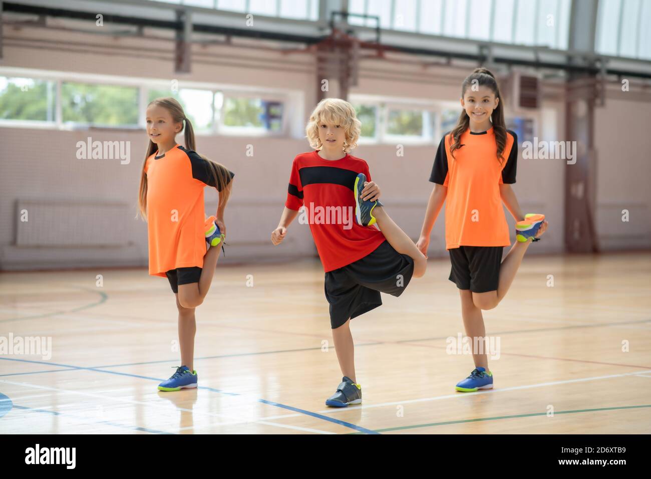 Three kids exercising in the gym and stretching legs Stock Photo - Alamy