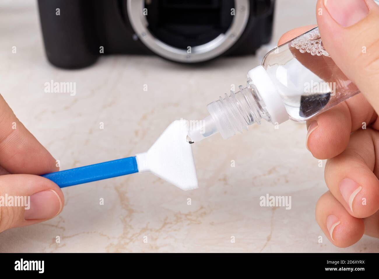 Applying a drop of sensor cleaner to the swab against dslr camera with ...