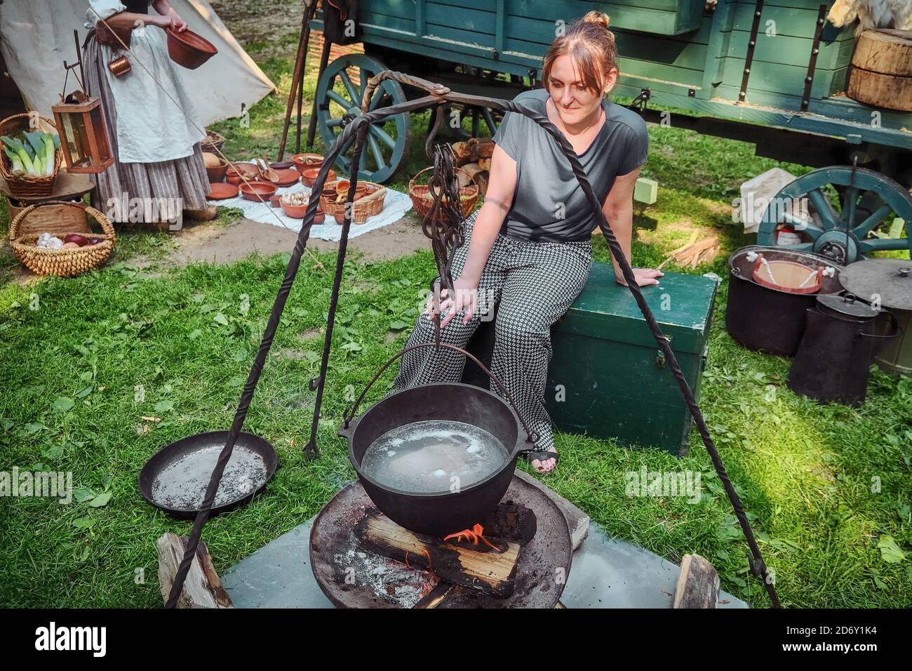 Cooking retro style in nature.. Woman sitting near the fire where the ...