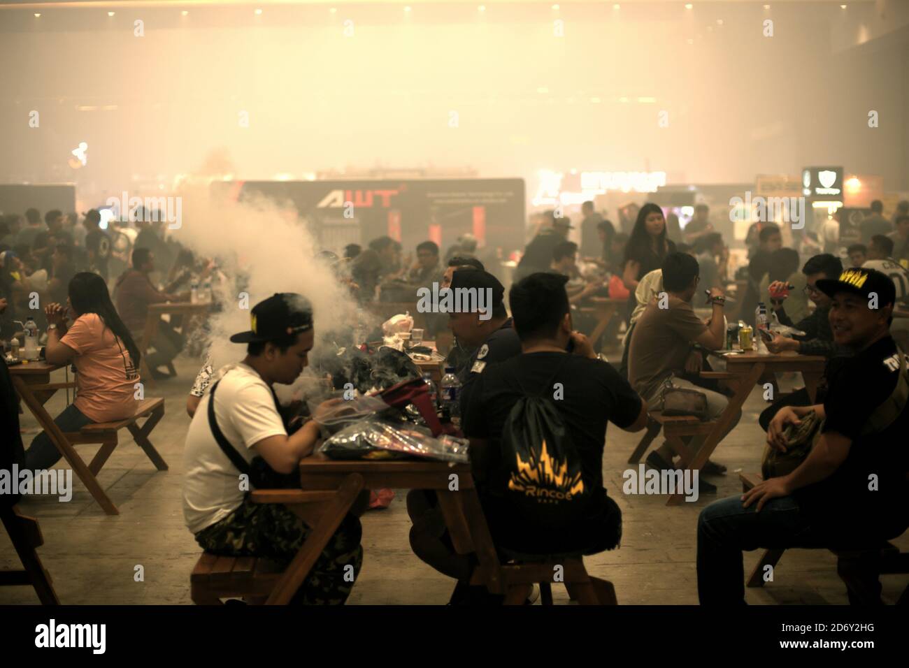 Visitors having meals and enjoying e-cigarette vapours on food court ...