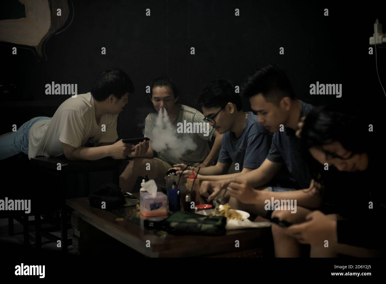 Vaping enthusiasts having leisure time with meals and e-cigarette vapours inside a vape cafe in ...