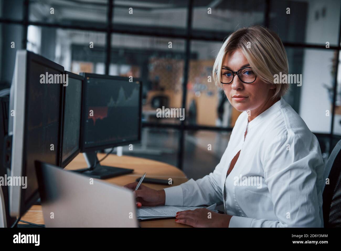 Female stockbroker in formal clothes works in the office with financial ...