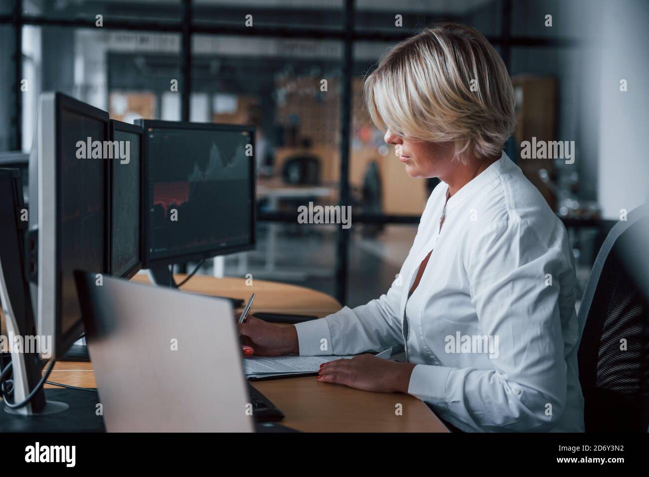 Female stockbroker in formal clothes works in the office with financial ...