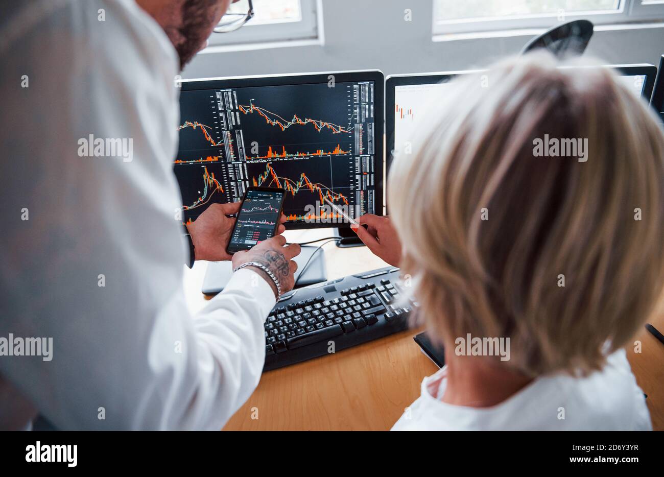 Two stockbrokers in formal clothes works in the office with financial ...