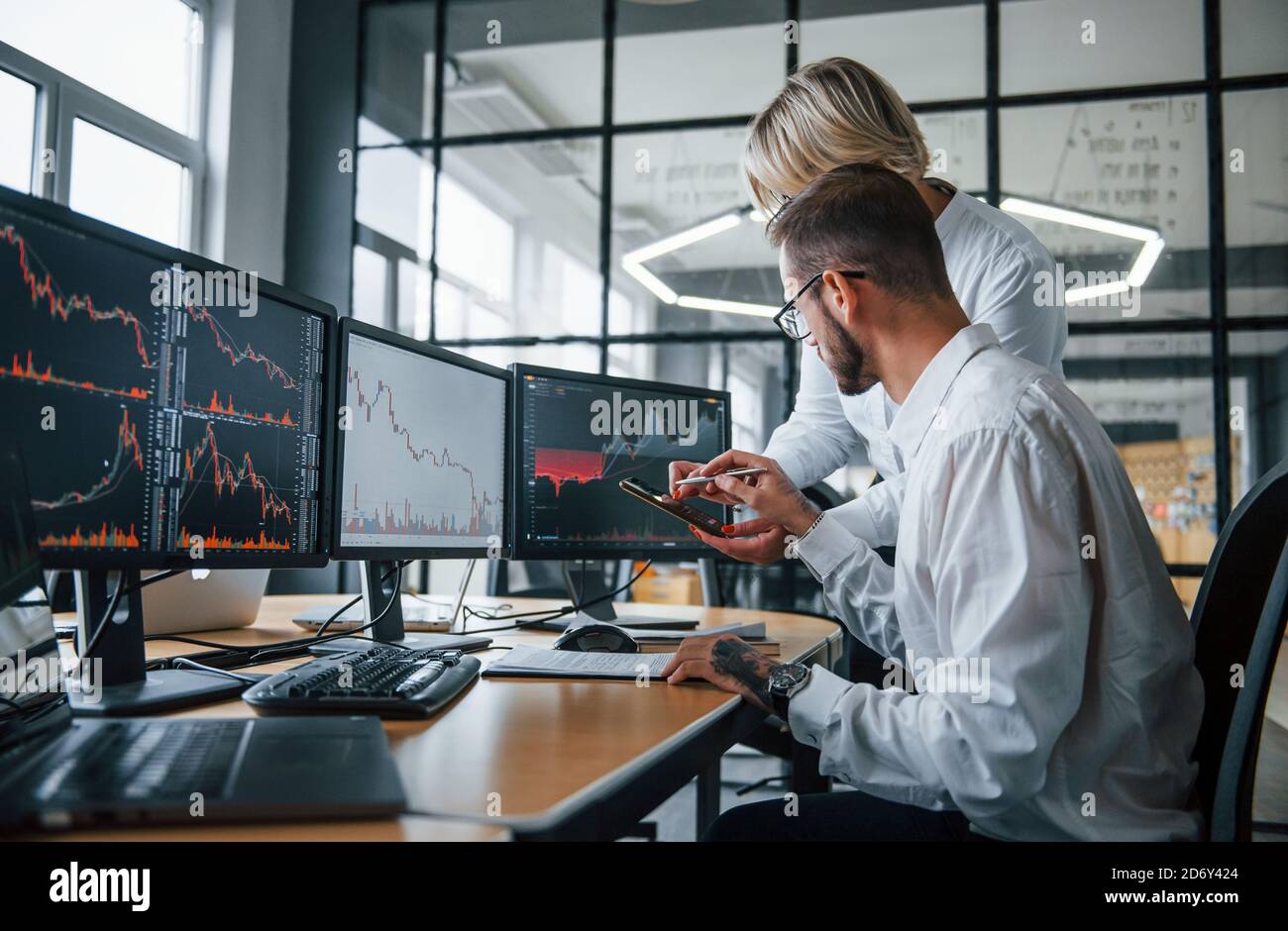 Two stockbrokers in formal clothes works in the office with financial ...