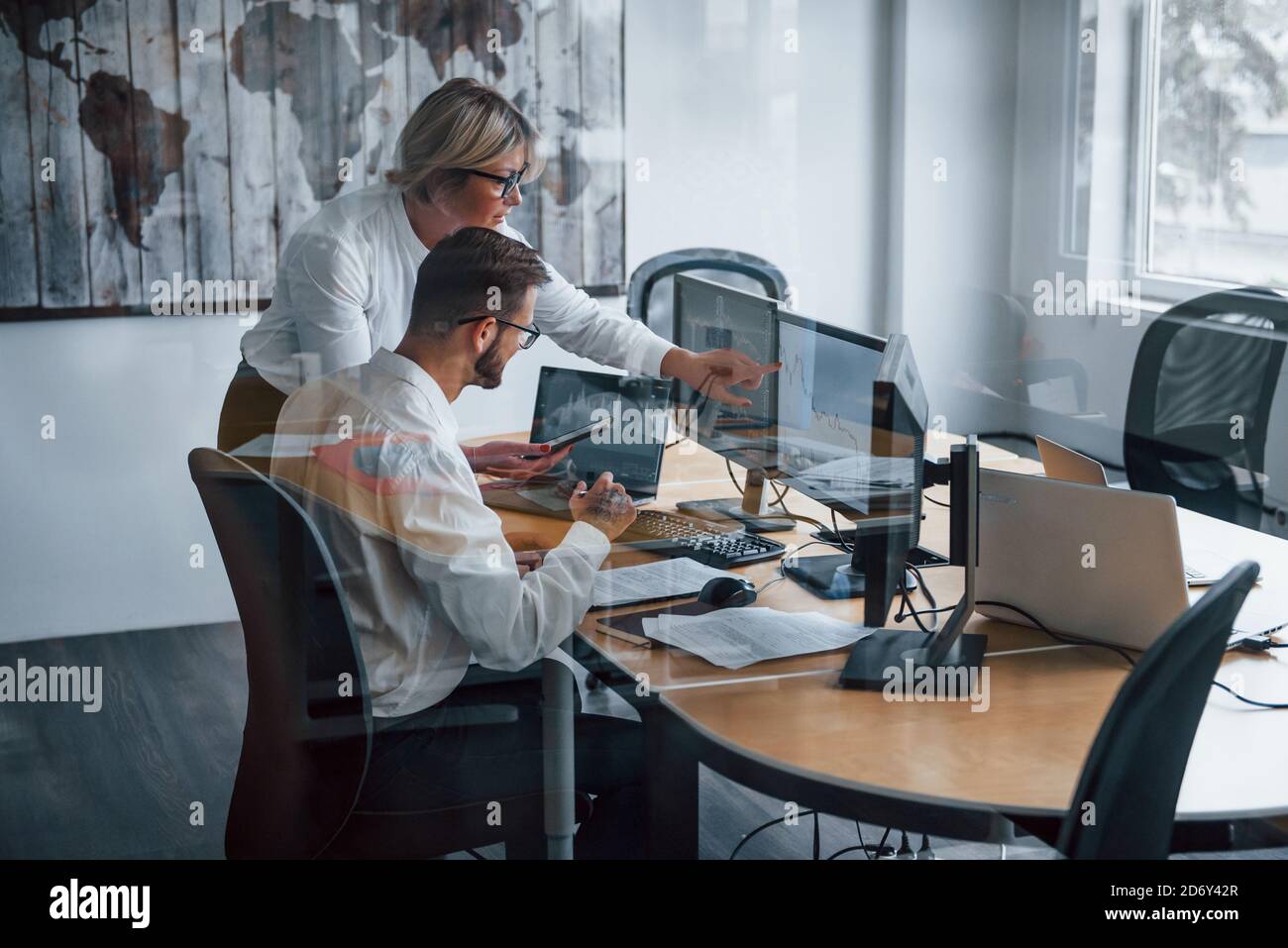 Two stockbrokers in formal clothes works in the office with financial ...