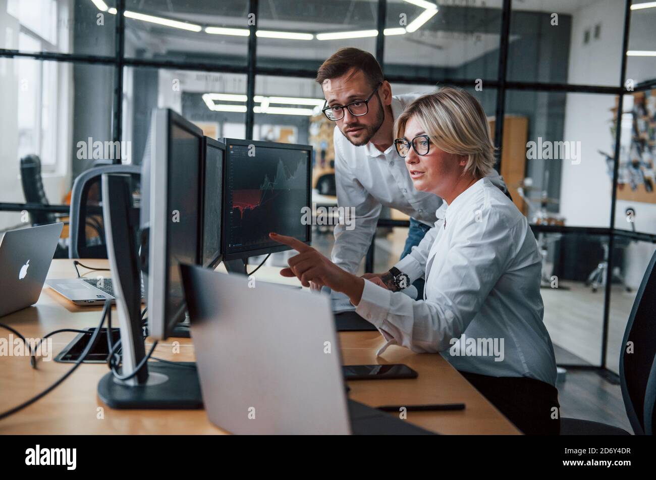 Two stockbrokers in formal clothes works in the office with financial ...