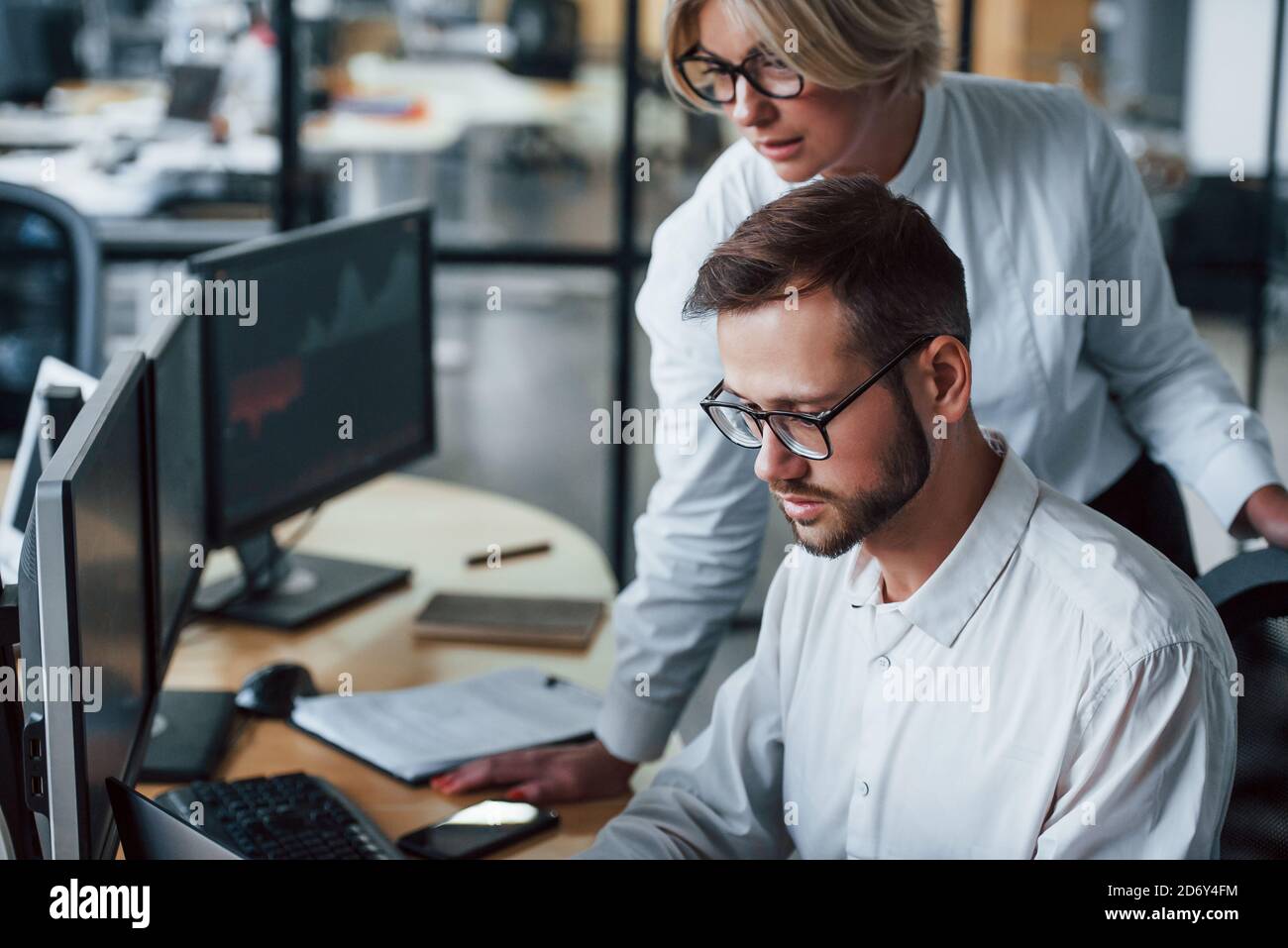 Two stockbrokers in formal clothes works in the office with financial ...