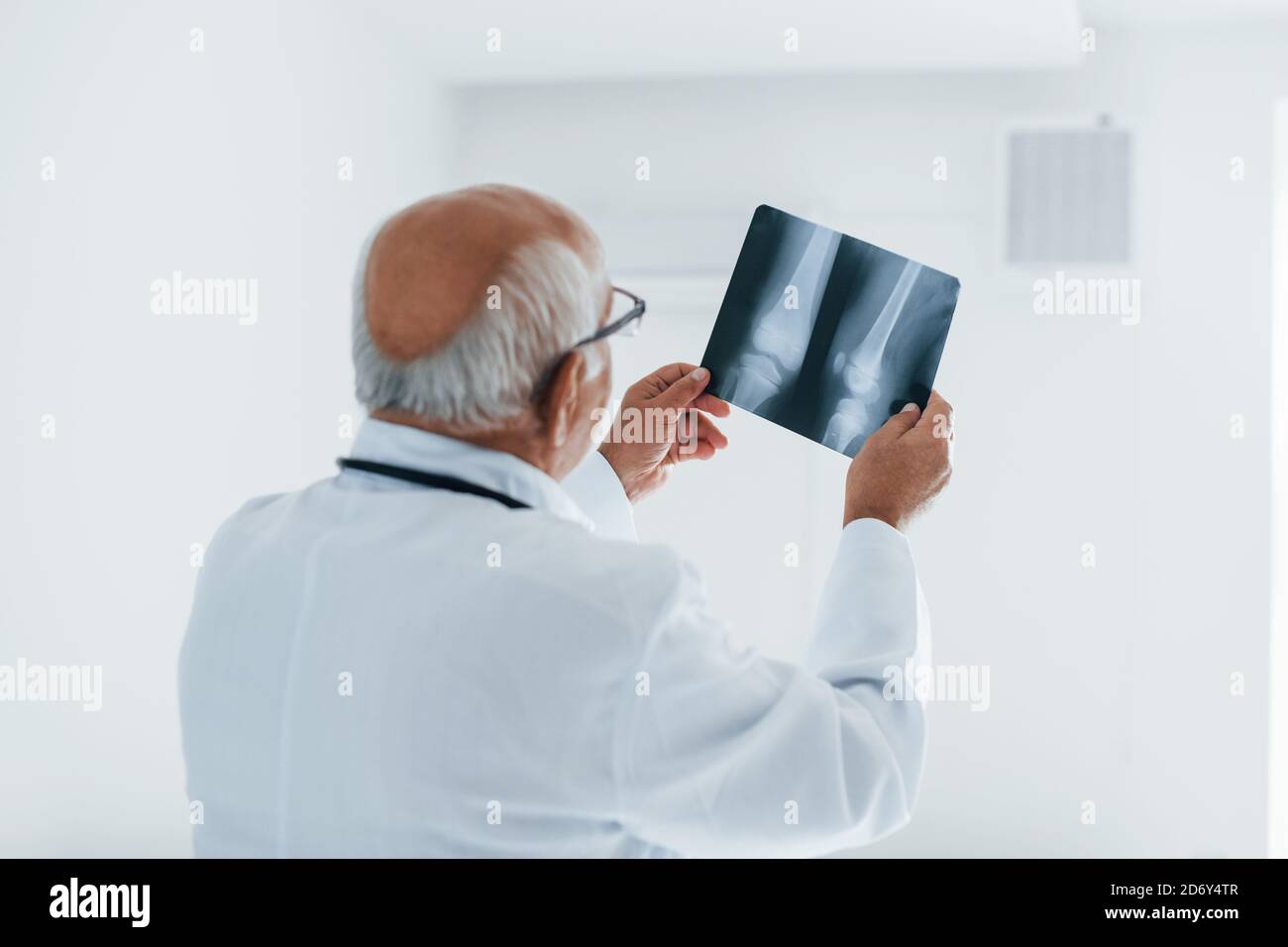 Senior man doctor in white uniform examines x-ray of human legs Stock ...