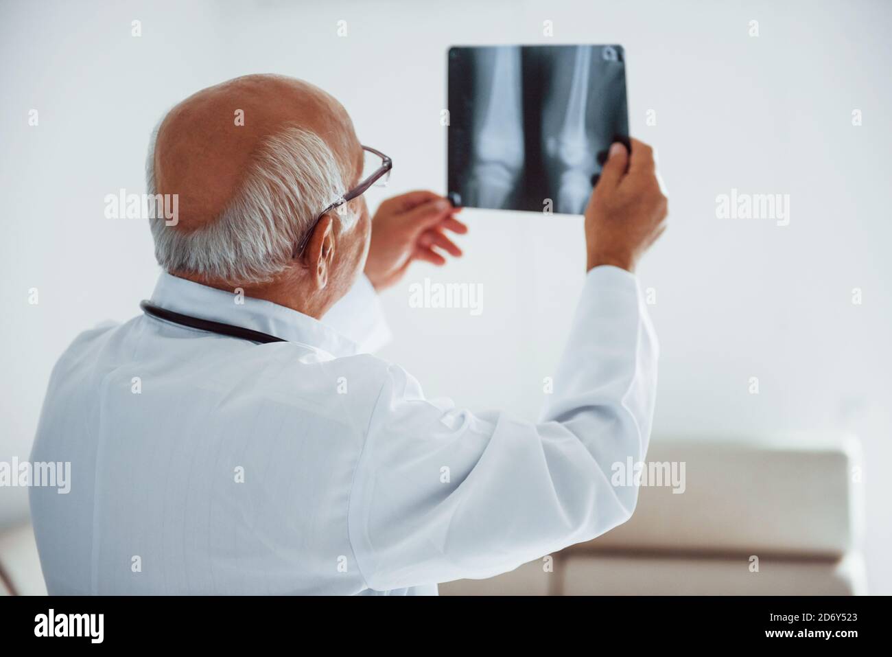 Senior man doctor in white uniform examines x-ray of human legs Stock ...