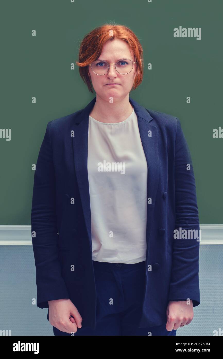 Portrait of a young teacher with a sad face near school blackboard ...