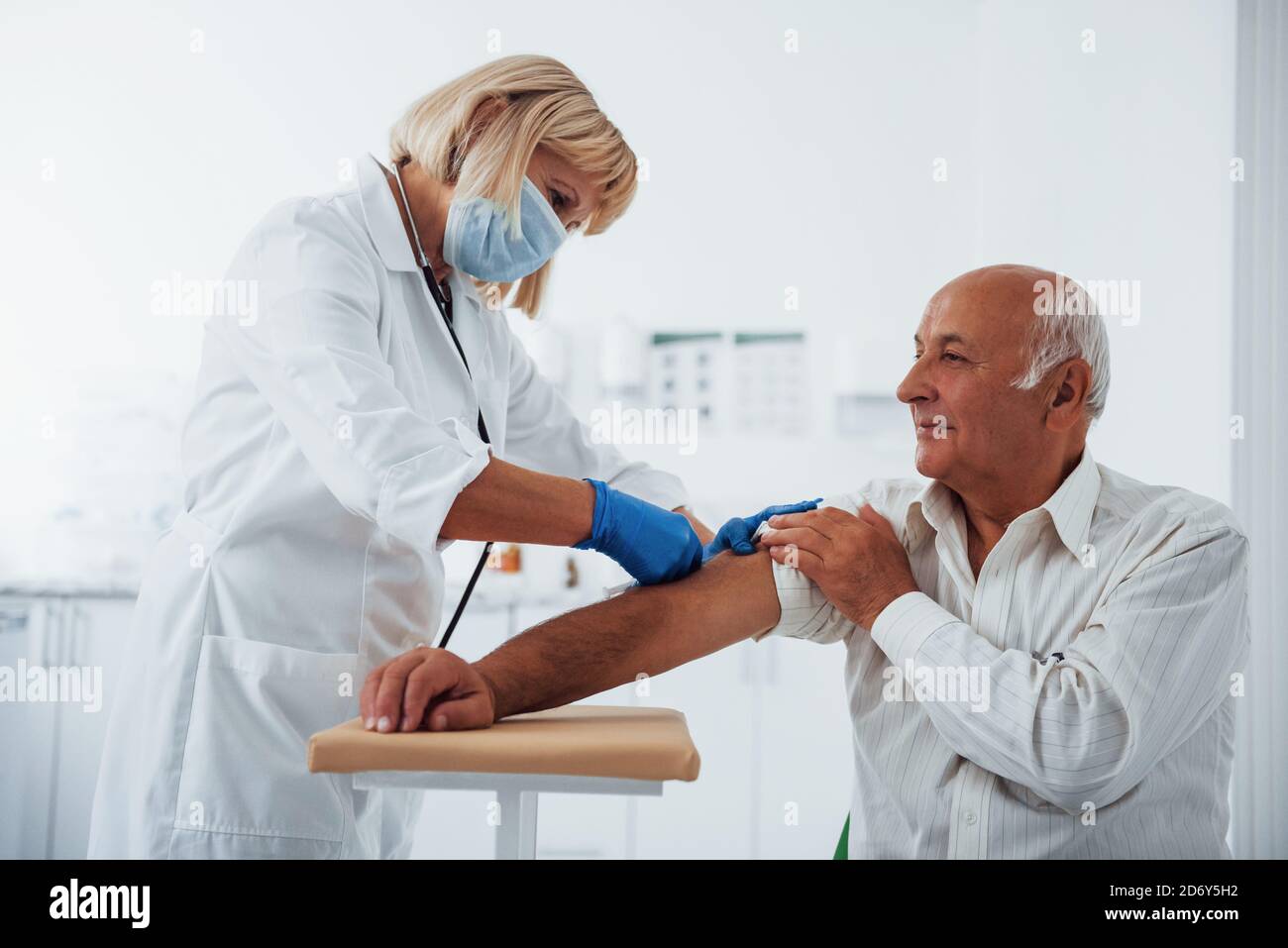 Female doctor injecting senior male patient with syringe in the clinic ...