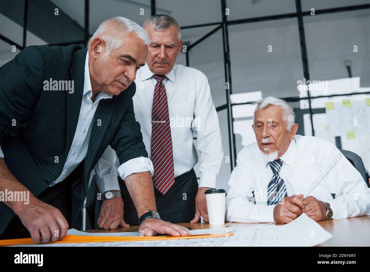 Planning construction by measuring it on paper. Aged team of elderly ...