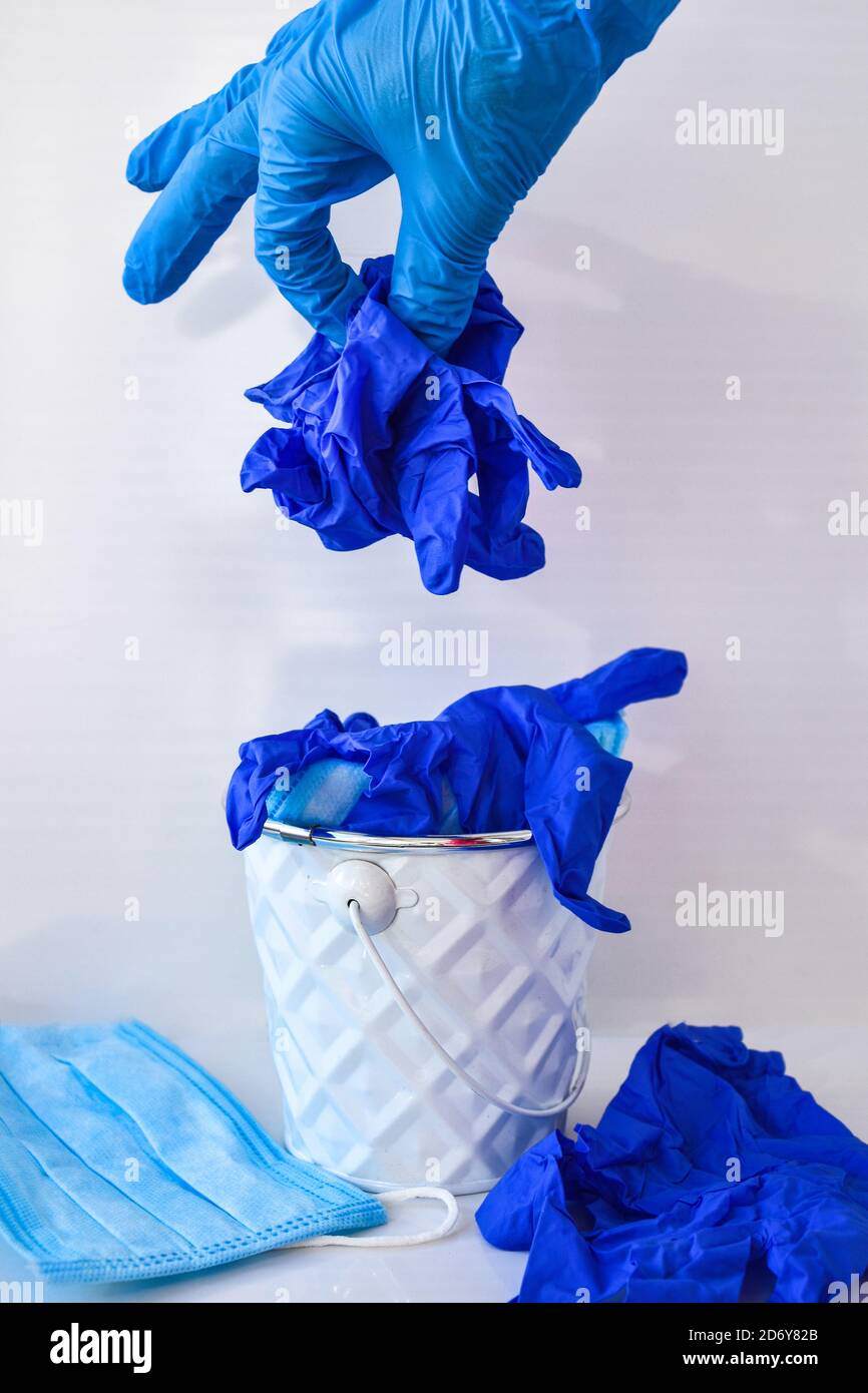 Hand throwing away used infectious masks and medical glove in the trash ...