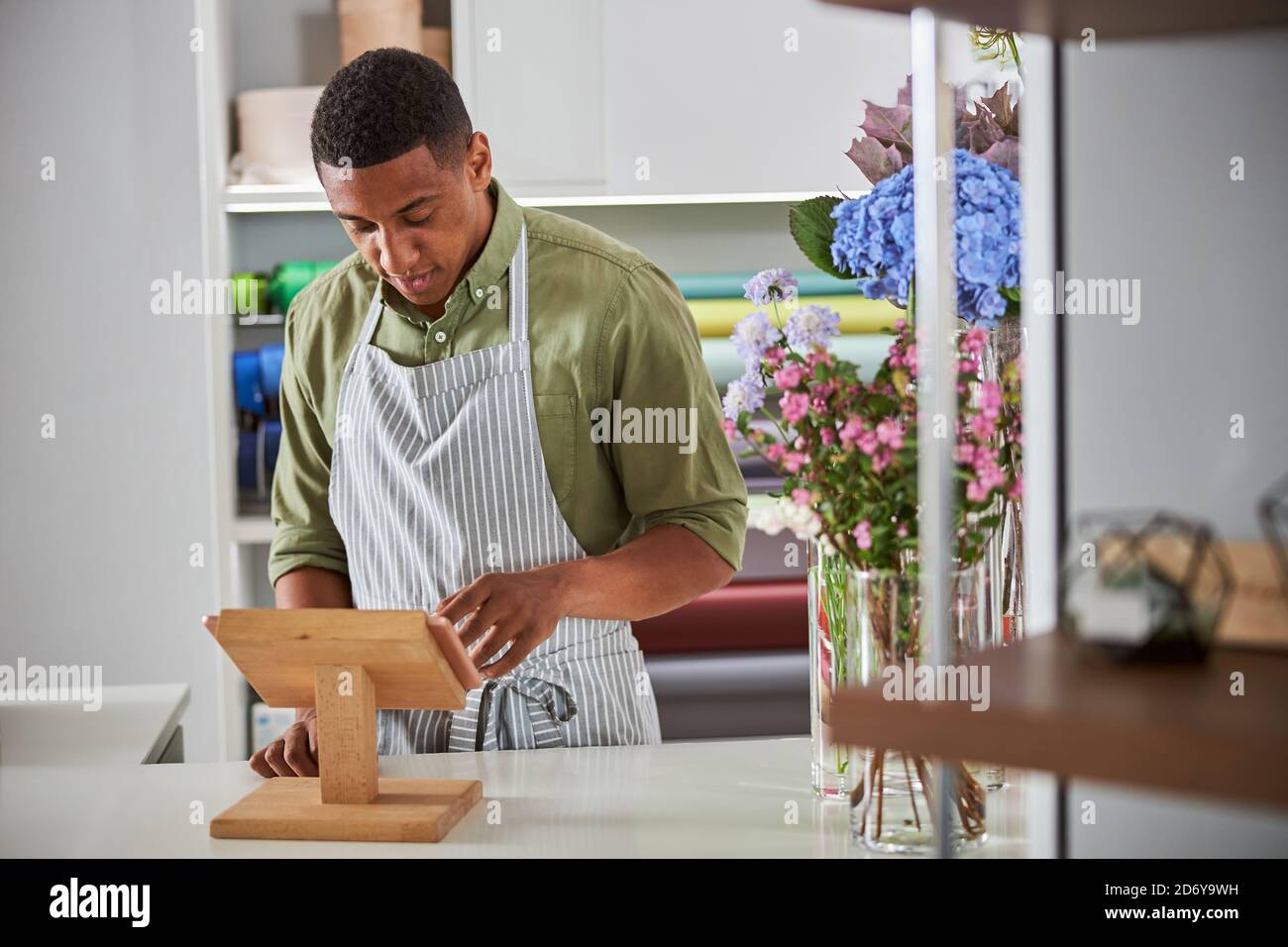 Cheerful young man working in flower shop Stock Photo - Alamy
