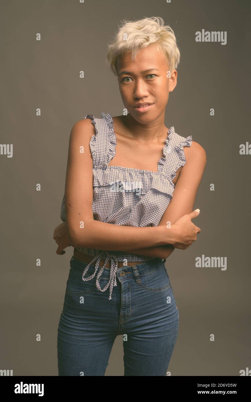Young beautiful rebellious woman with short hair against gray ...