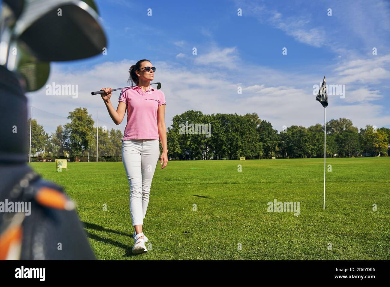 Female golfer walking on the green grass Stock Photo - Alamy