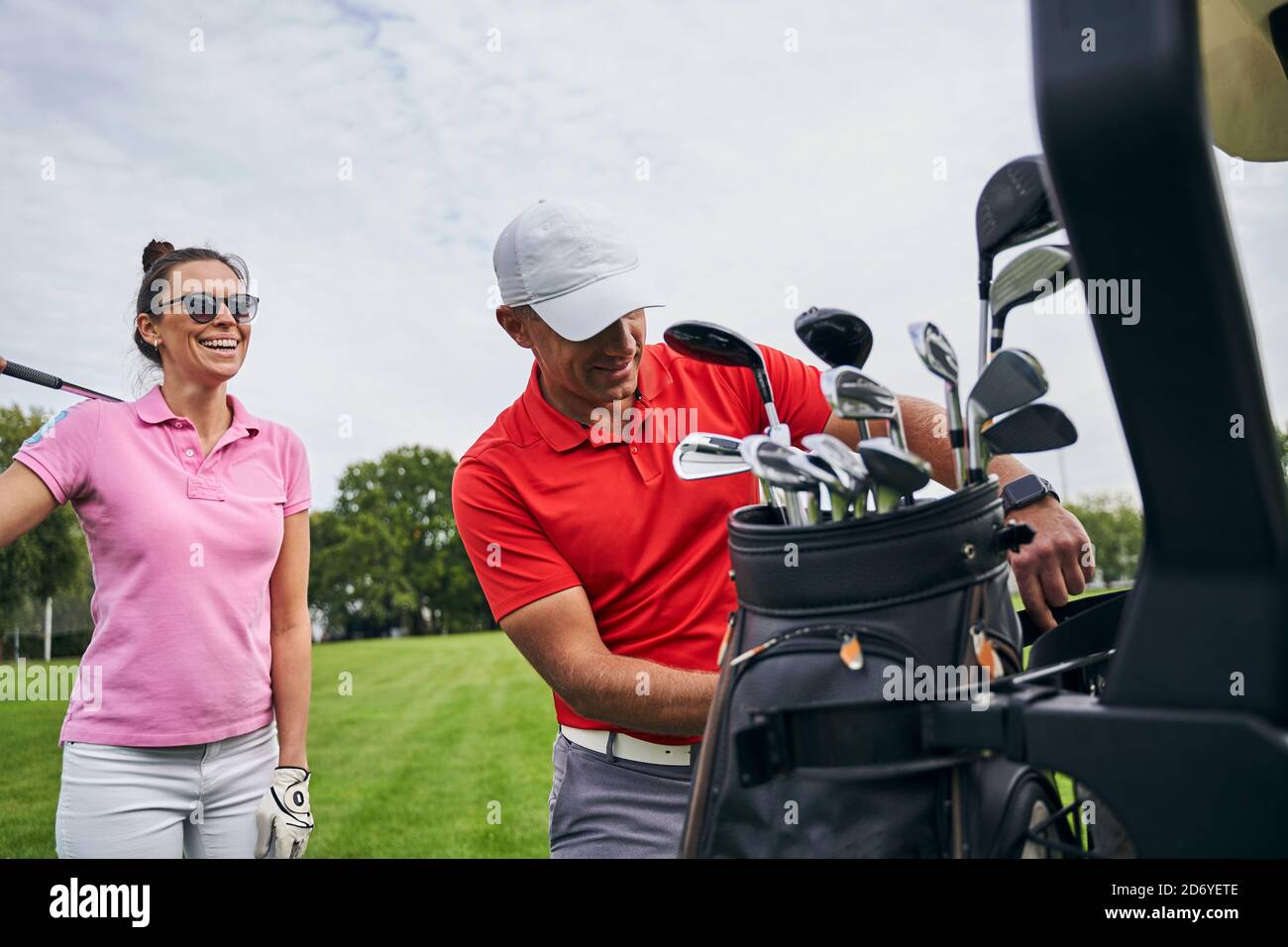 High-spirited sporty lady standing behind her golf instructor Stock ...