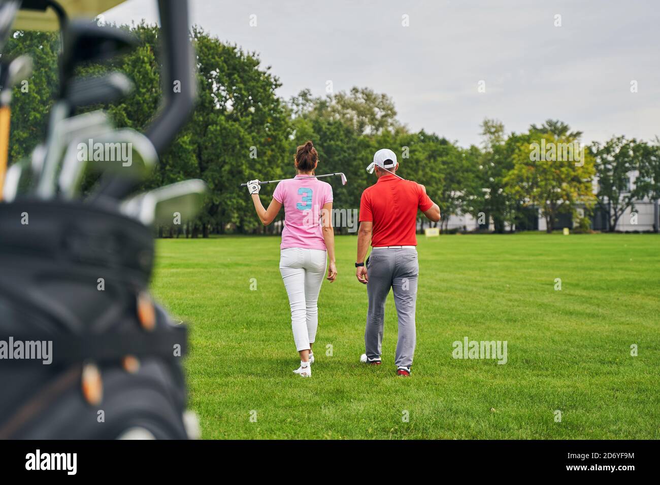 Two adult Caucasian golf players walking ahead Stock Photo - Alamy