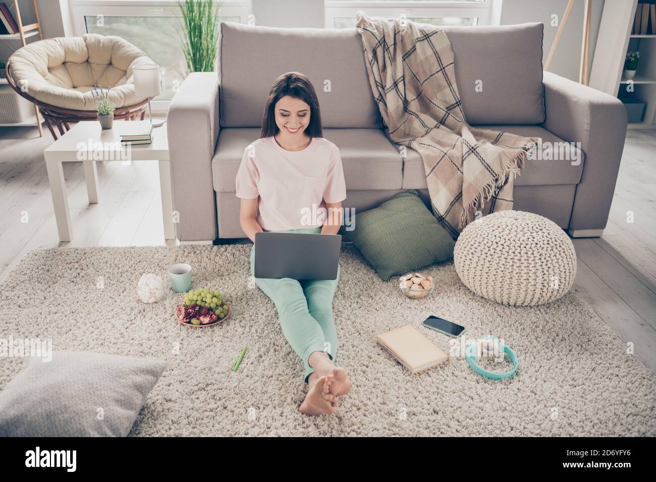 Photo portrait of young girl sitting on floor rug with laptop plates of ...
