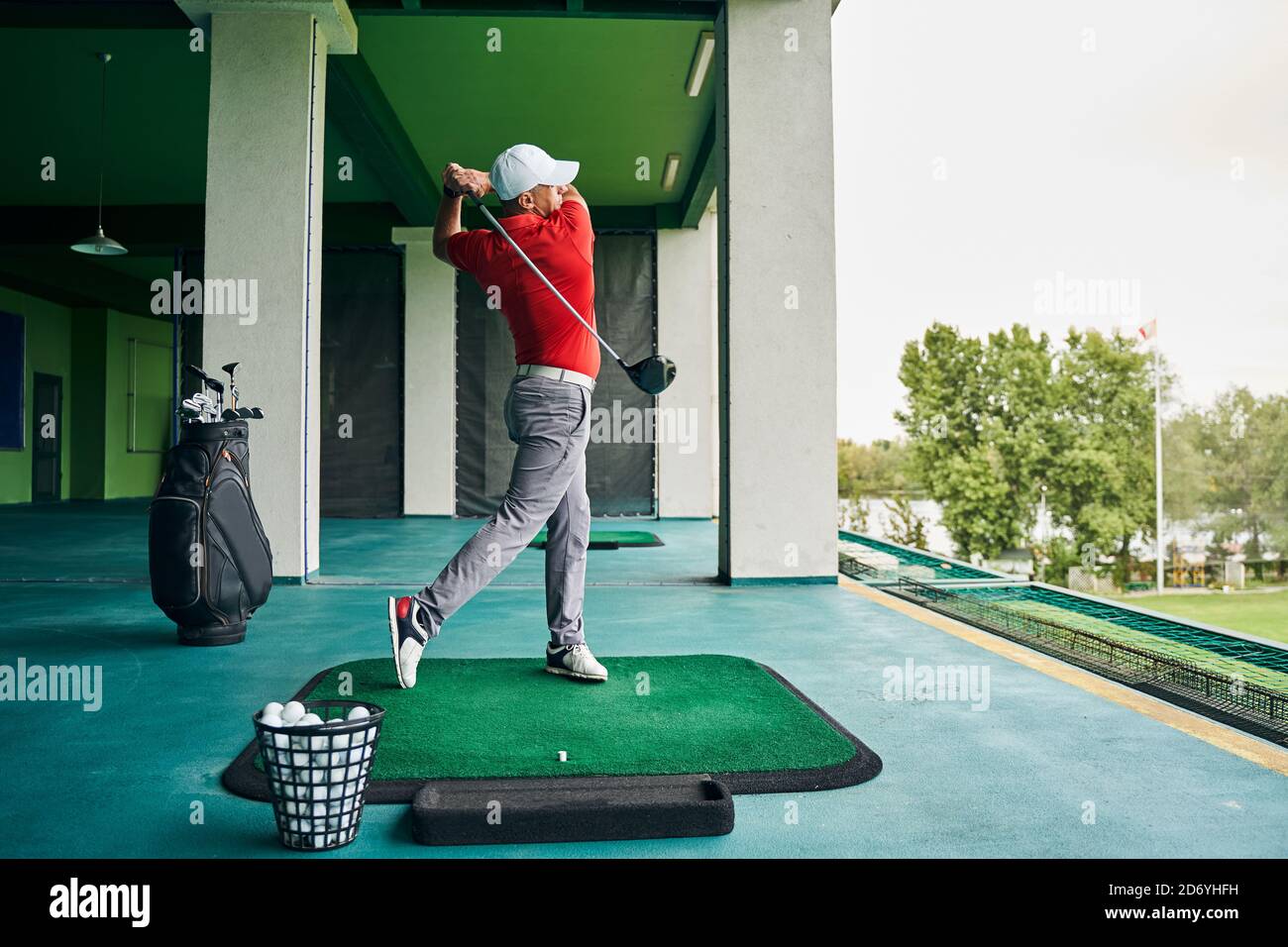Man exercising on the golf hitting mat Stock Photo - Alamy