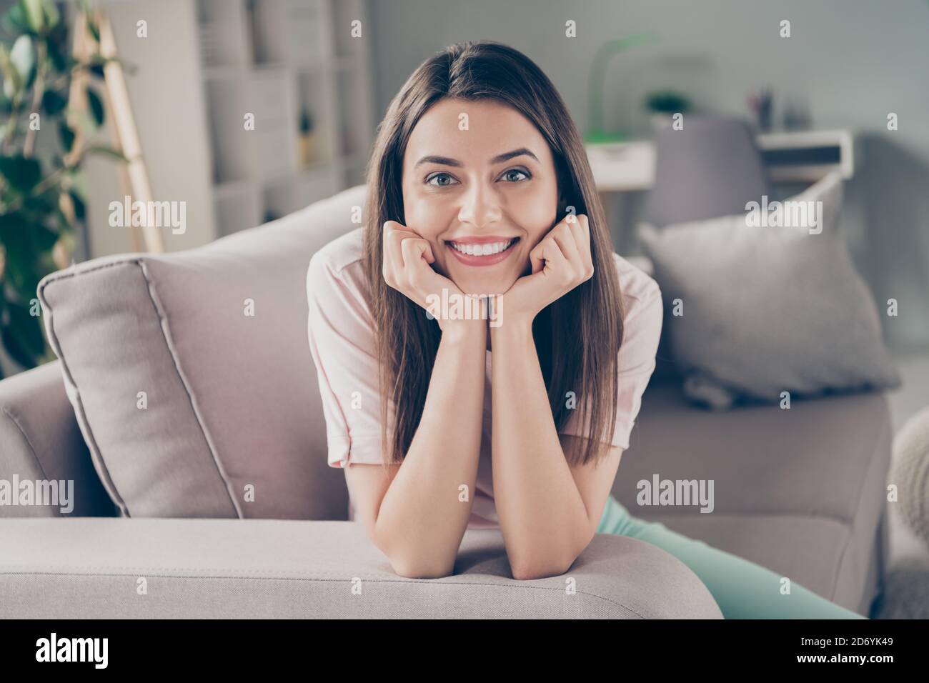 Photo portrait of cute girl smiling sitting on couch holding face with ...