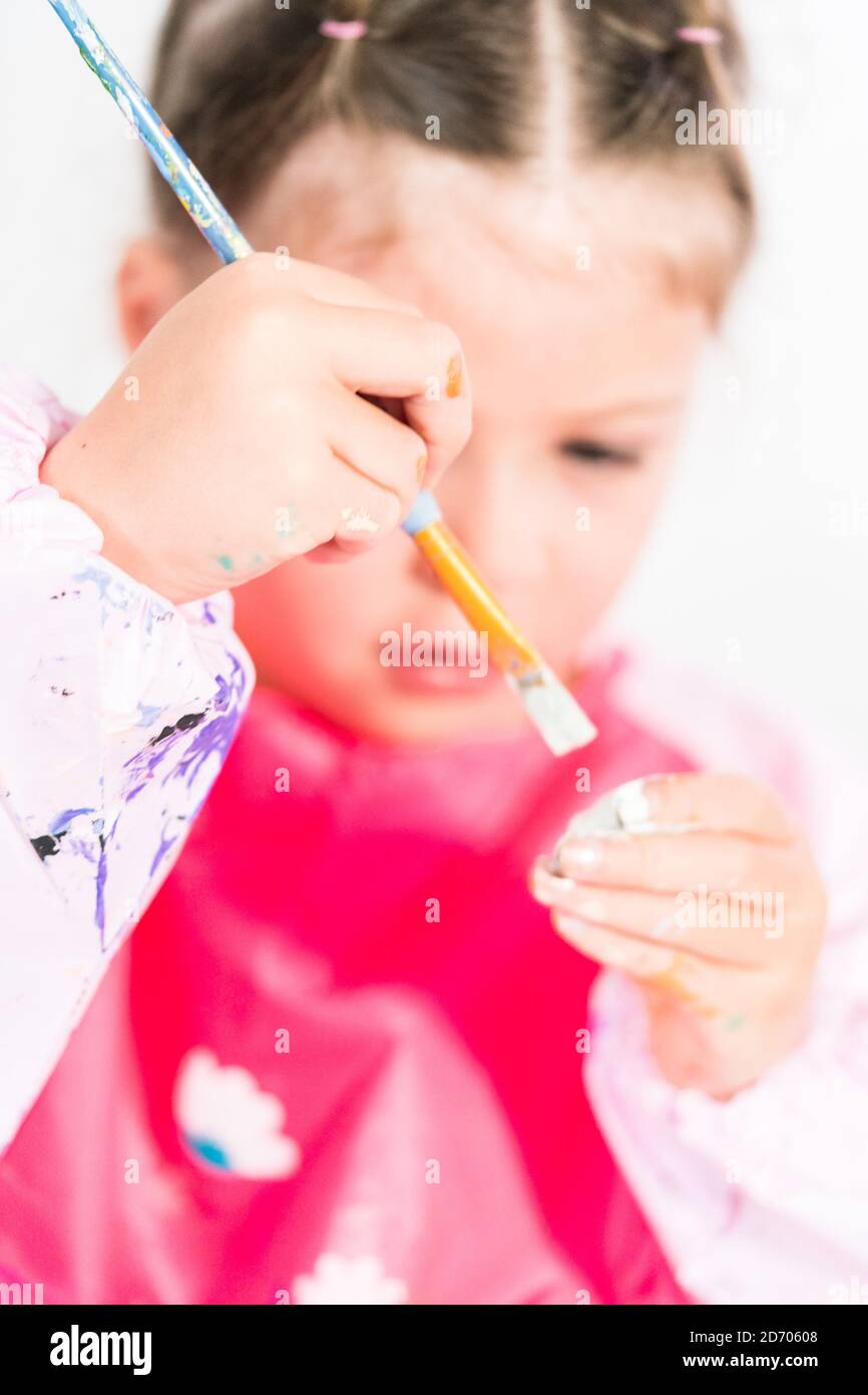 Little girl painting mermaid tails made out of modeling clay with ...