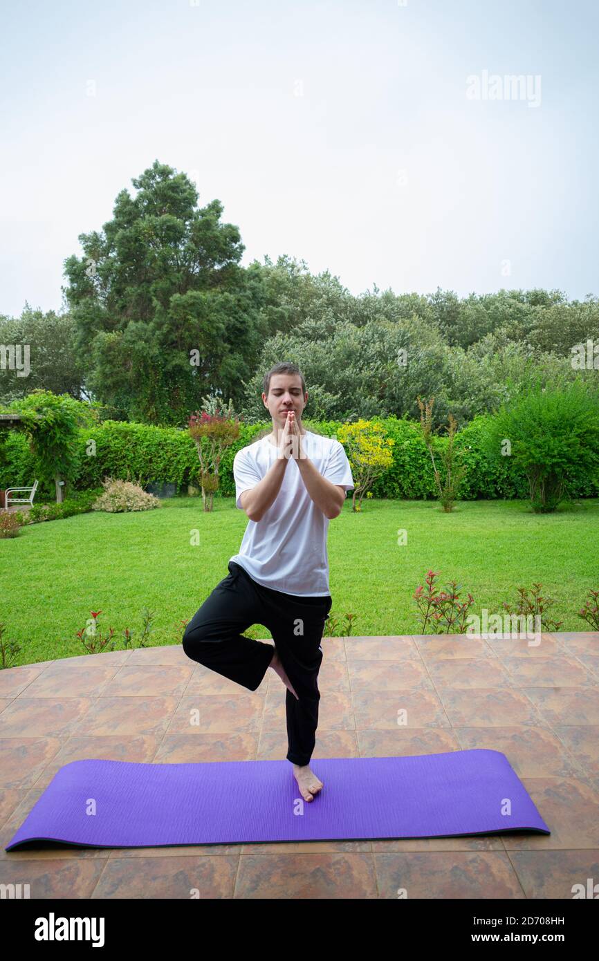 Man doing tree pose while practicing yoga in home garden Stock Photo ...