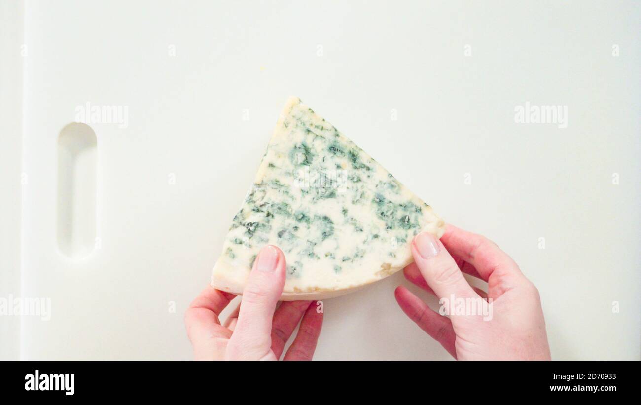 Flat lay. Slicing a large slice of gourmet cheese on a white background ...