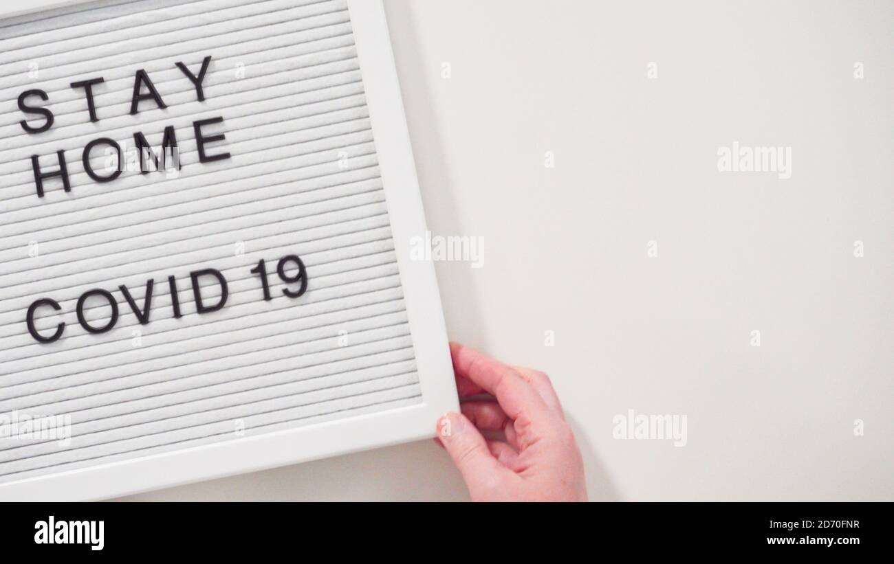 Flat lay. STAY HOME and COVID-19 sign on message board with a blue ...