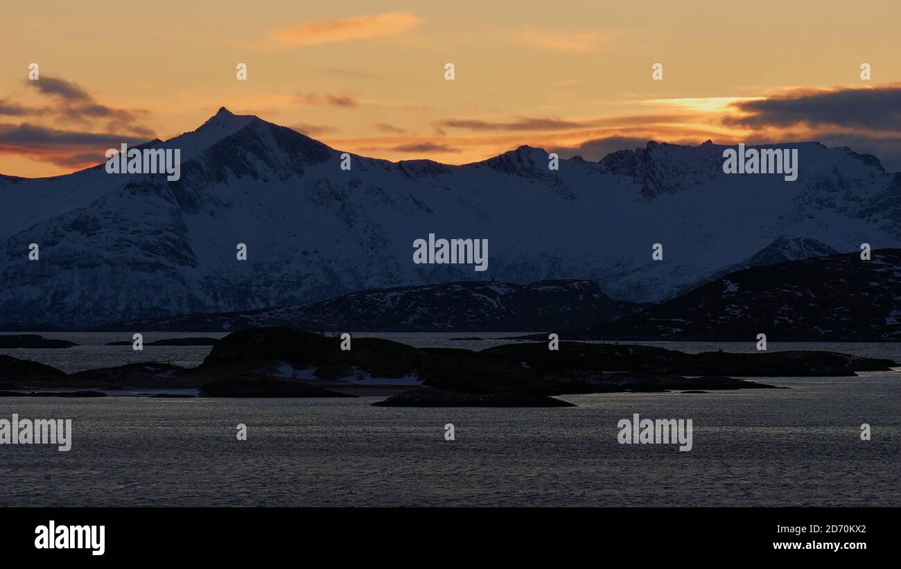 Stunning view of snow-covered craggy mountains at the shore of a fjord ...