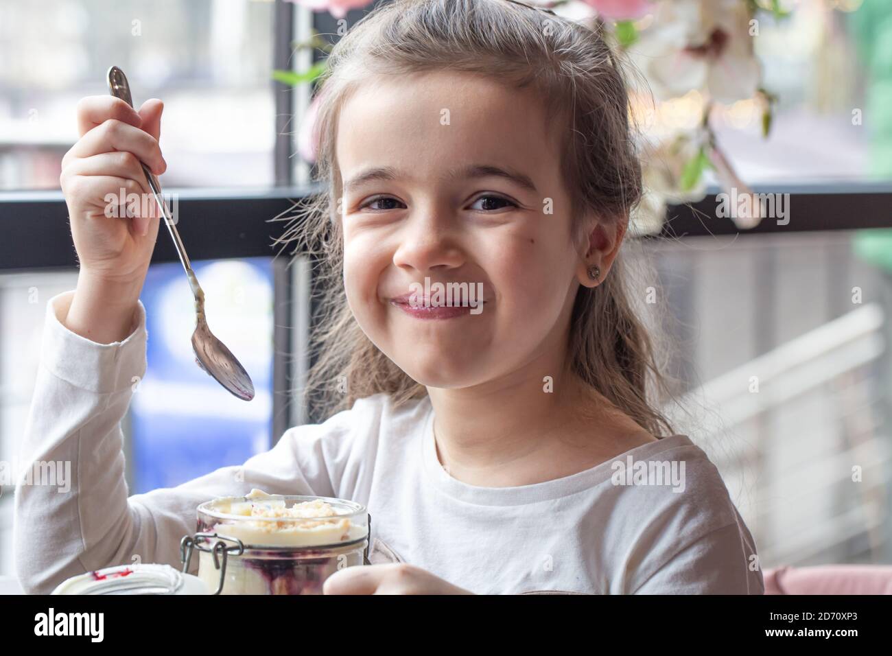 Beautiful little girl eating dessert in a cafe Stock Photo - Alamy