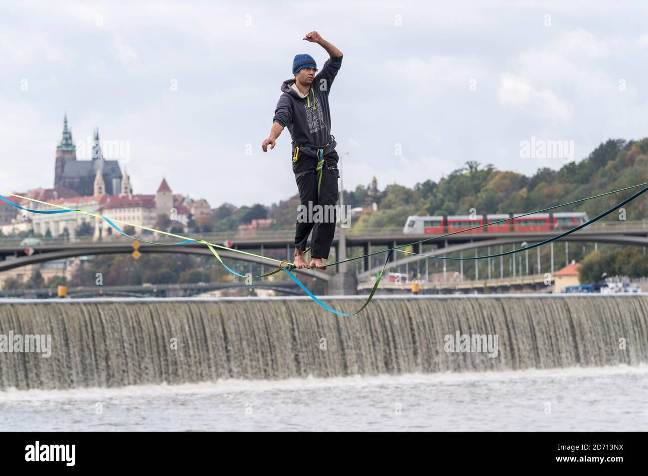 a tightrope walker on slack line above the Vltava river with background ...