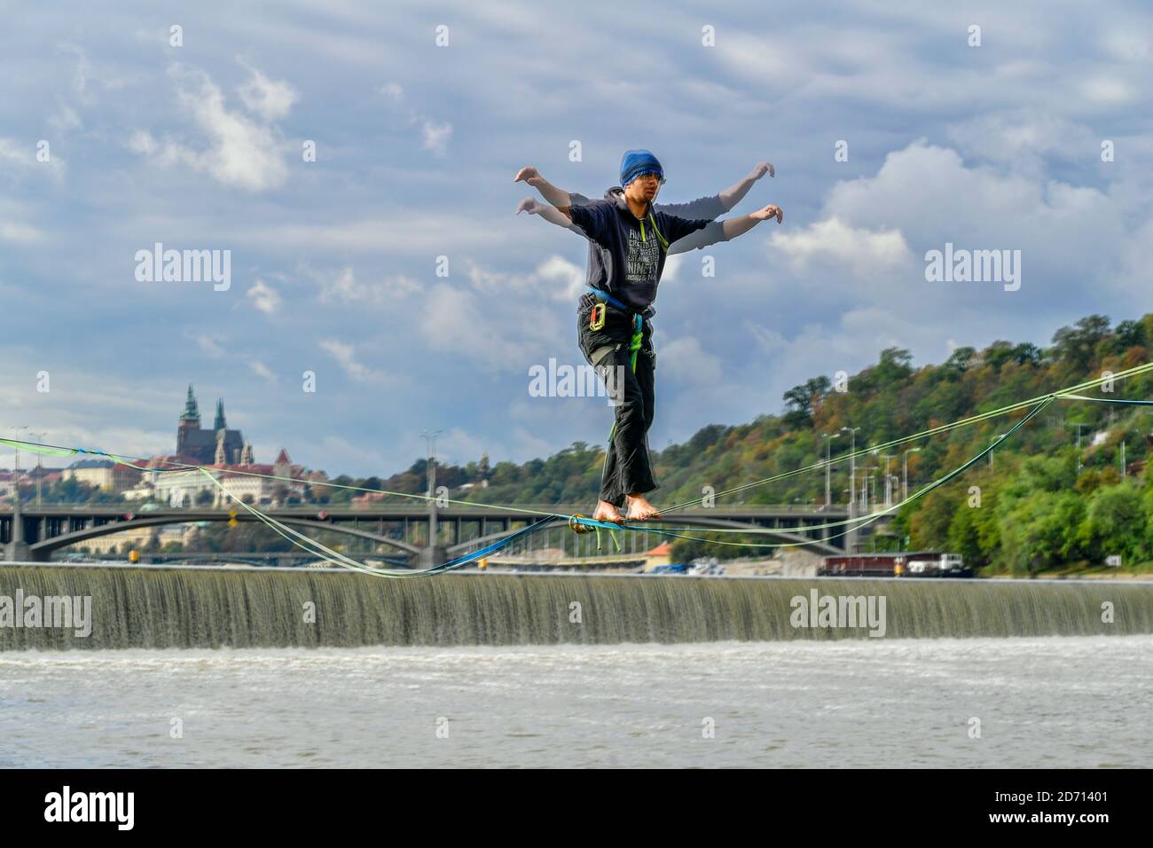 a tightrope walker on slack line above the Vltava river with background ...
