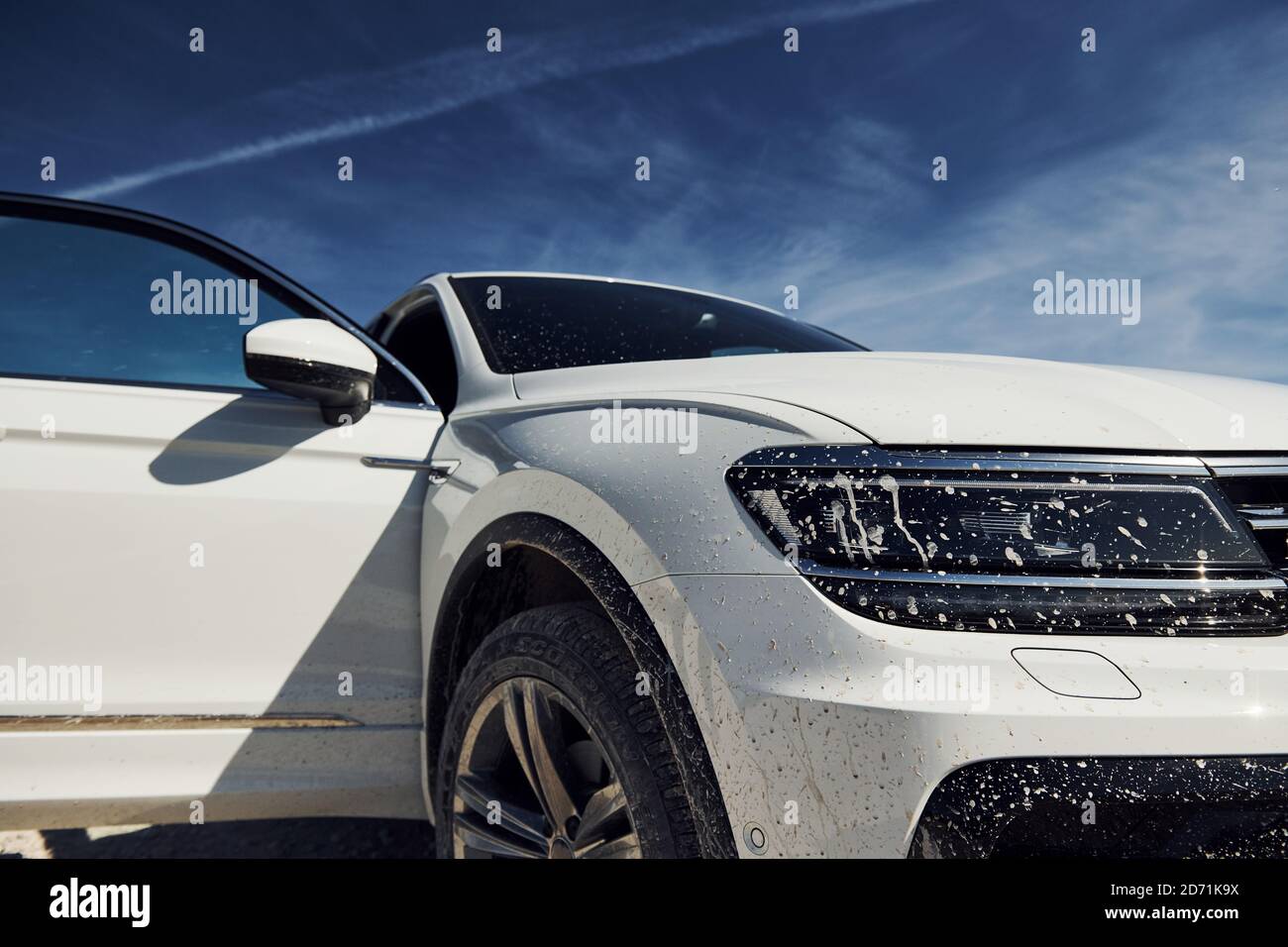 Front view of white modern car parked outdoors against blue sky at ...