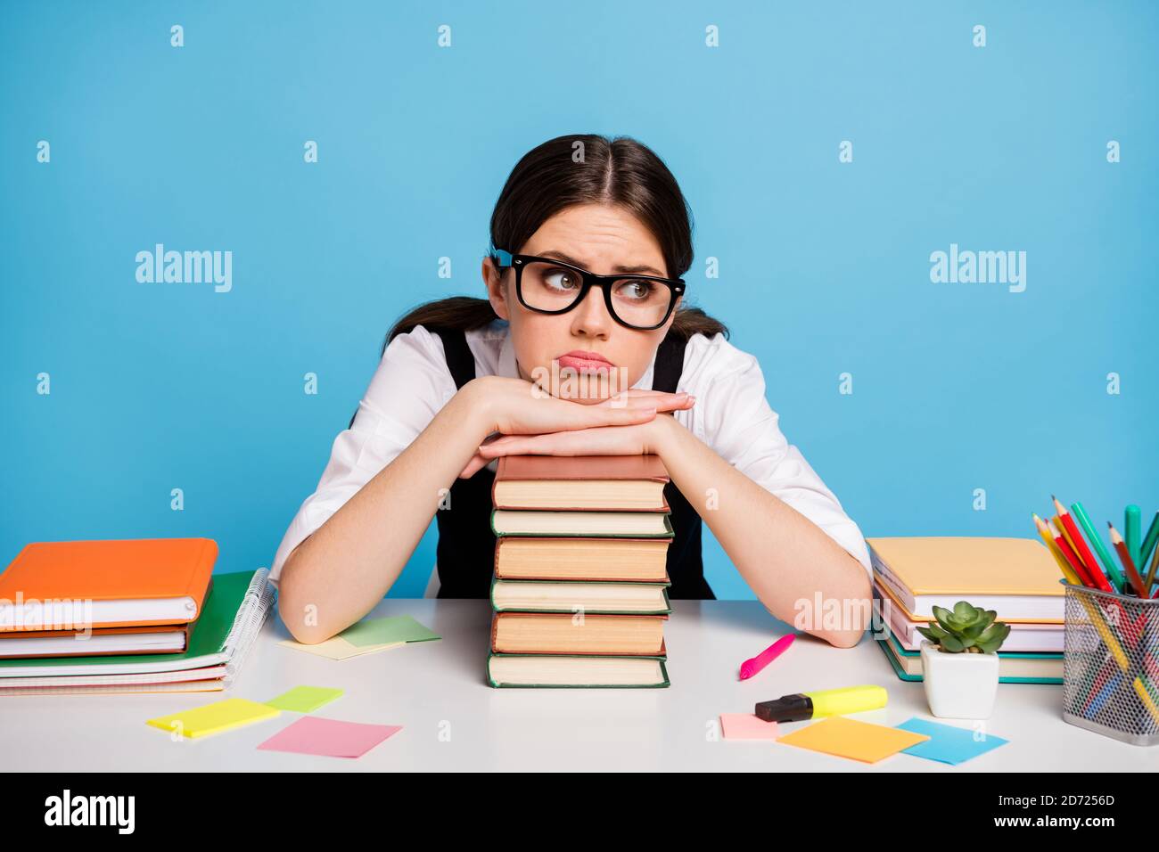 Photo of frustrated girl college student sit table put hands head pile ...