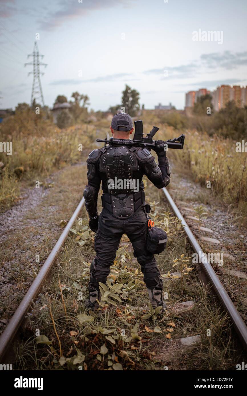 a man with a rifle in uniform stands with his back Stock Photo - Alamy
