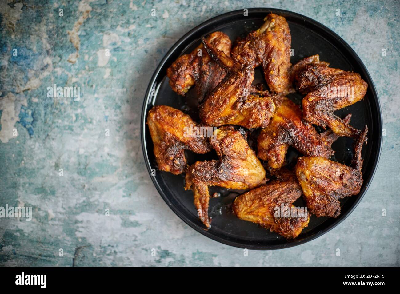 Grilled chicken wings on a black ceramic plate. Placed on a stone Stock ...
