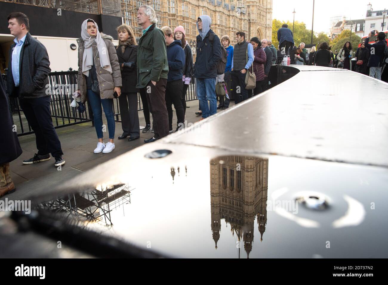 Staff and visitors queue to enter the House of Commons, which is ...