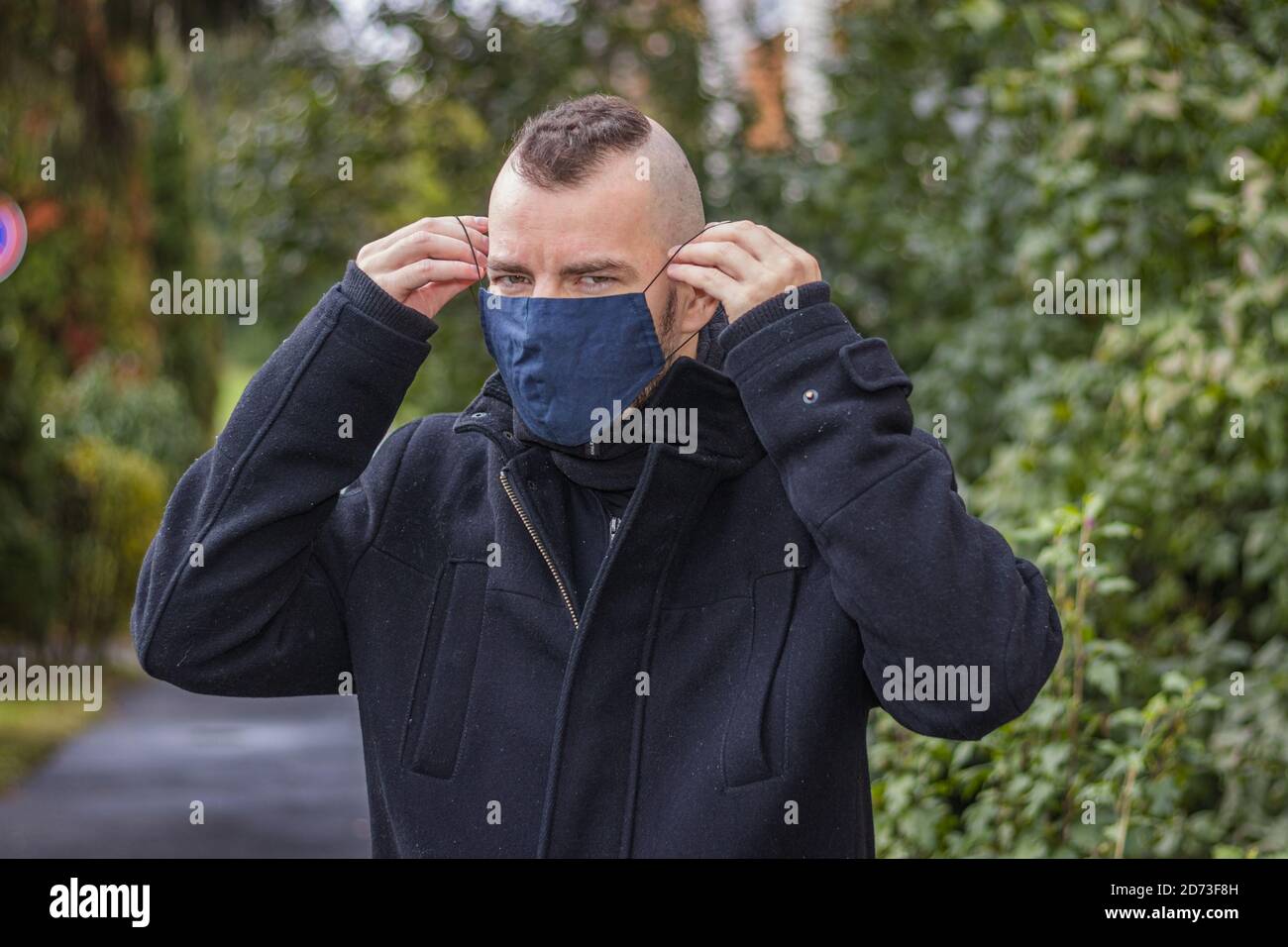 A man puts on his mask in the dripping rain in a small city in Hungary ...