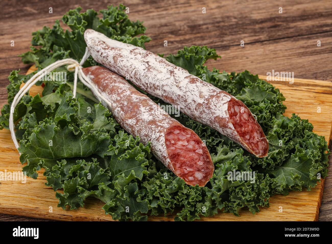 Spanish Fuet sausage with salad leaves over wooden background Stock ...