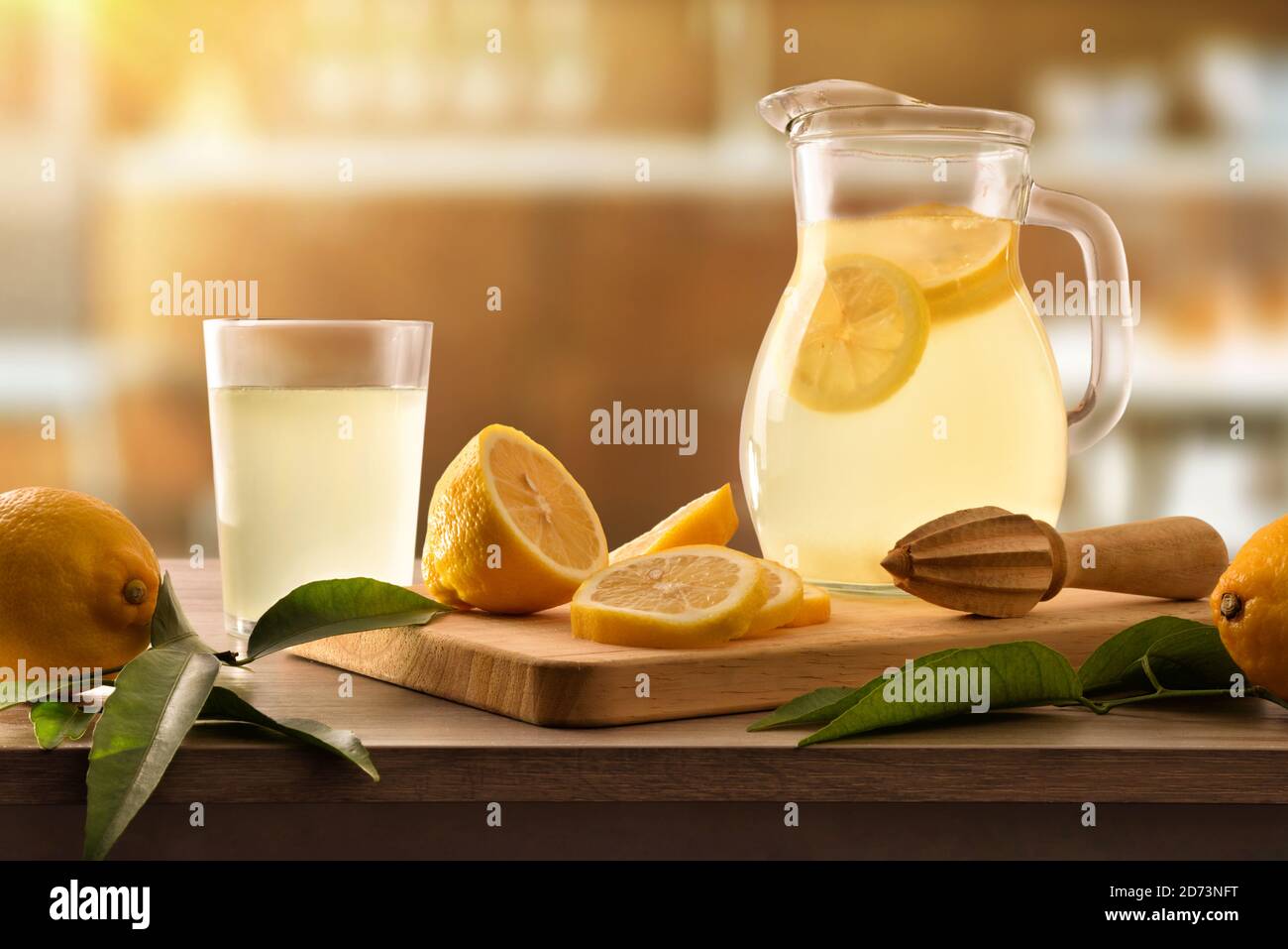 Freshly prepared lemon juice with utensils on wooden kitchen bench ...