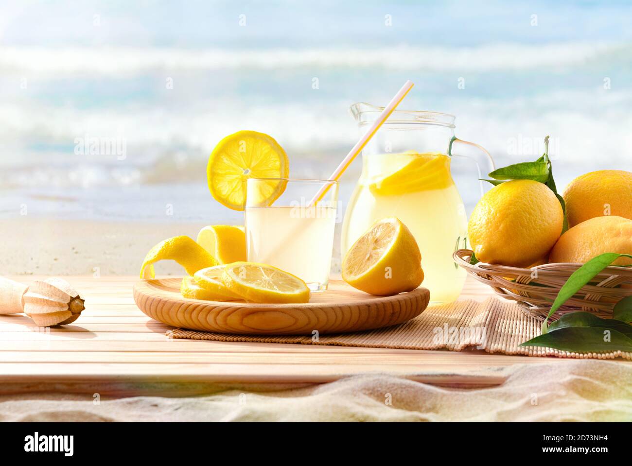 Freshly squeezed lemonade in glass and jug on wooden base with lemons ...