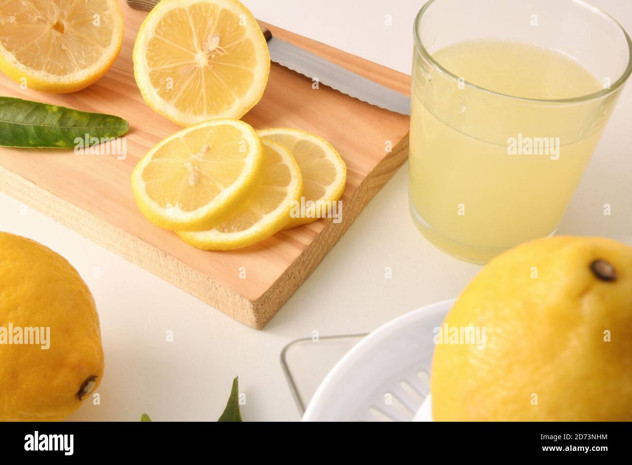 Lemon slices on cutting board and squeezed lemon in glass vase on white ...