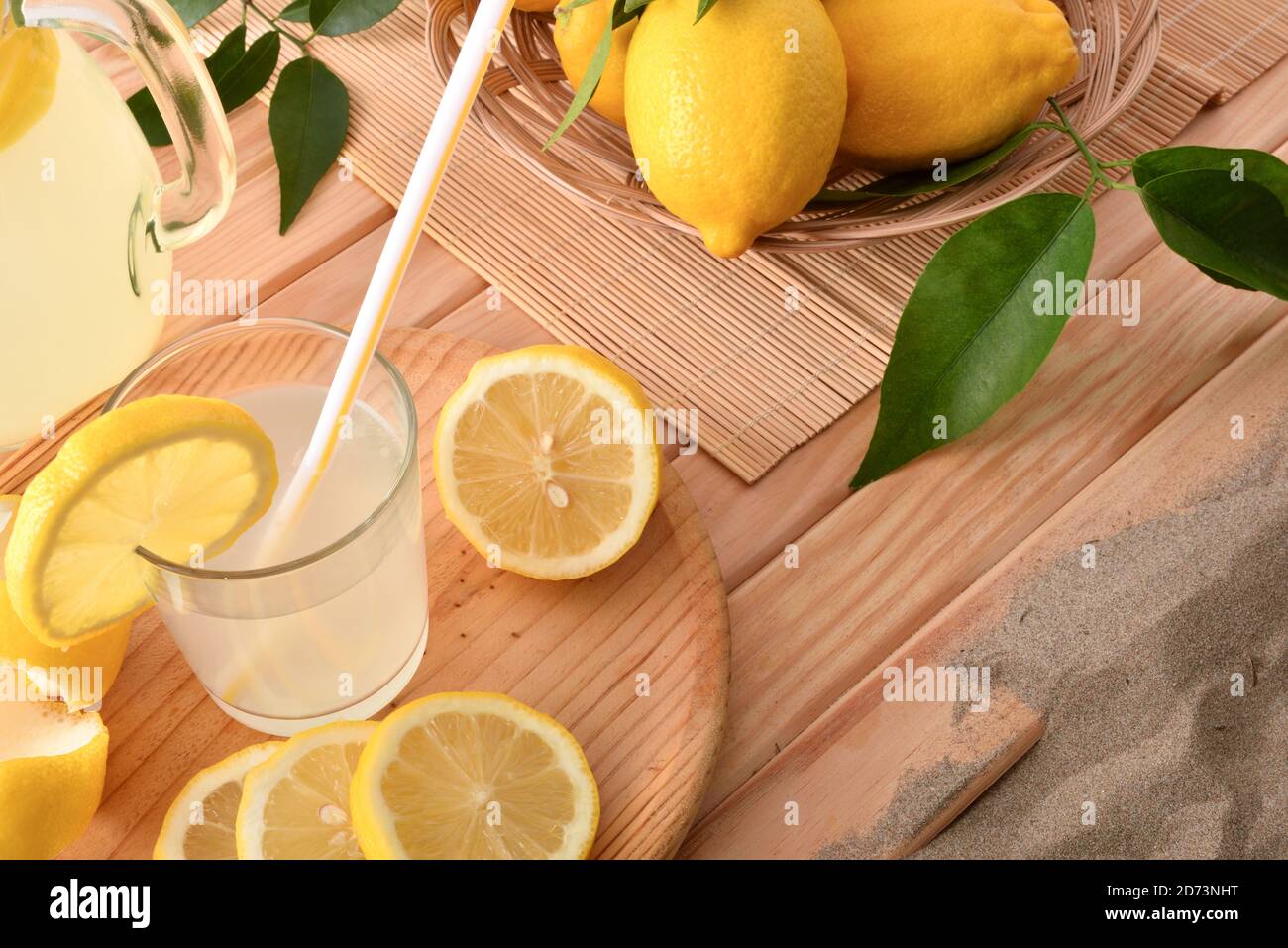 Freshly squeezed lemonade in glass on wooden base with lemons in beach ...