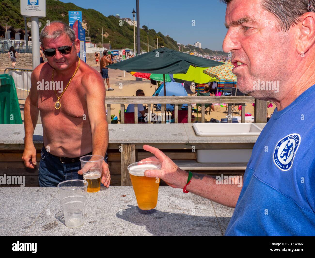 A Chelsea fan enjoys a pint with friends along Bournemouth beach Stock ...