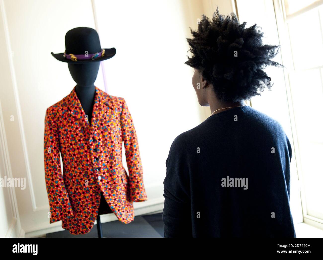 A visitor looks at a jacket and hat owned by Jimi Hendrix, exhibited in ...