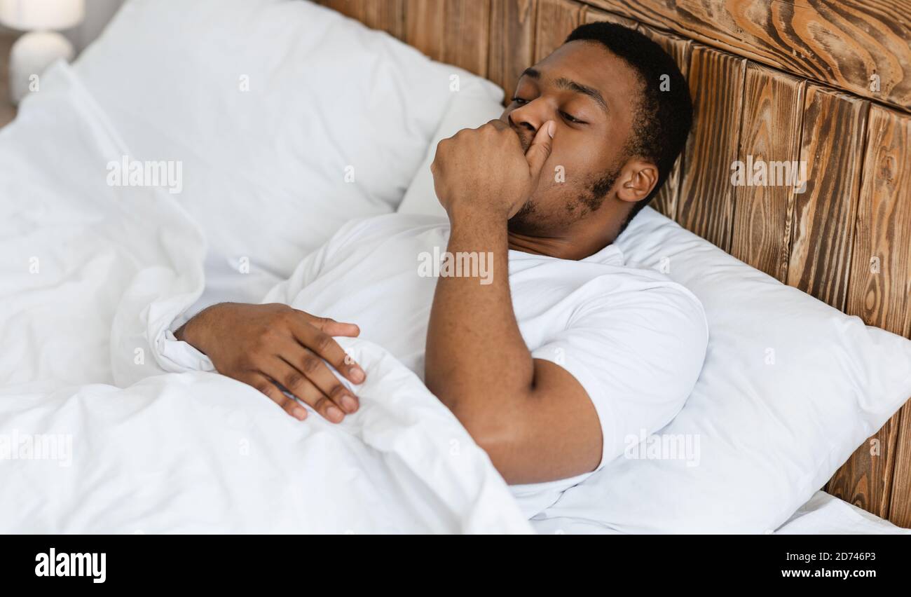 Sleepy Black Man Yawning Awakening Lying In Bed At Home Stock Photo - Alamy